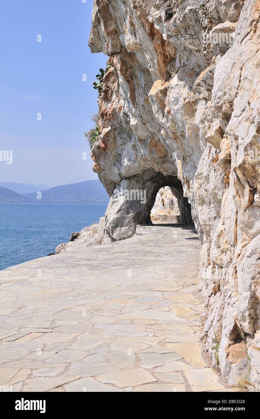 Coastal footpath with an arch in the rocks on the Acronauplia Peninsula ...