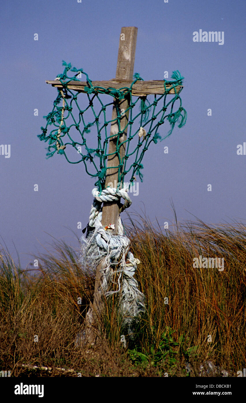 A wooden cross and old fishing nets mark a sacred spot on the beach at ...