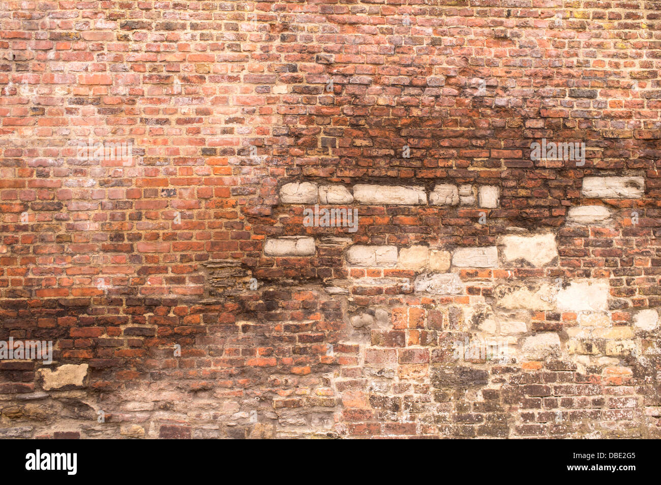 Old exterior brick and stone wall with numerous patched additions over ...