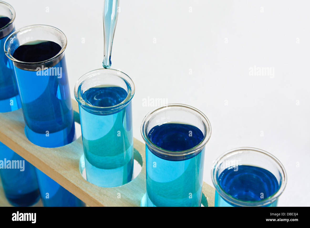 Close up of a dropper placing a solution in a test tube in a laboratory ...