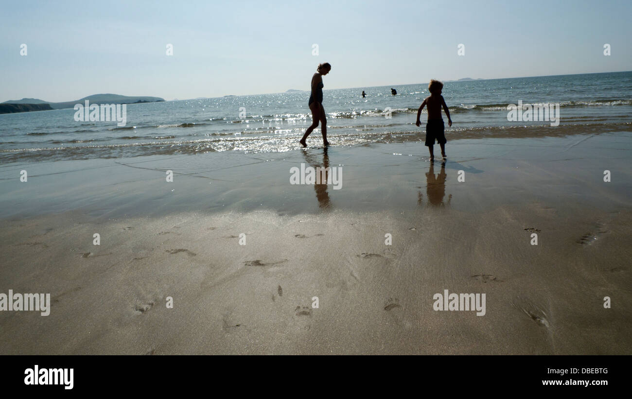 A mother and child wading in water on the shore at Whitesands Bay in ...