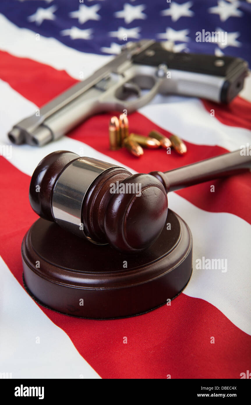 A wooden gavel on an American flag with a gun and bullets in the ...
