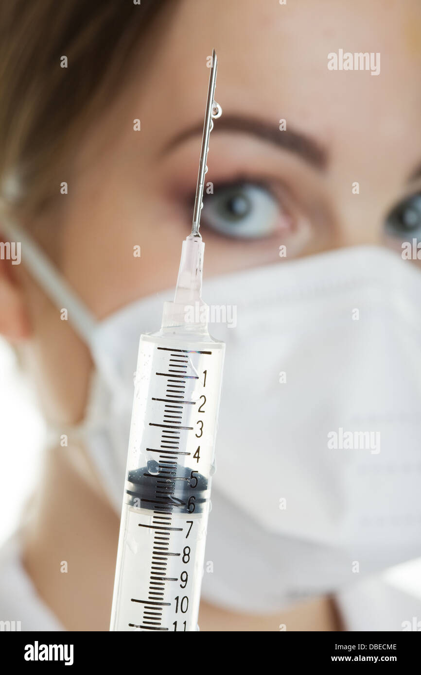 A nurse wearing a mask holding a large syringe Stock Photo - Alamy