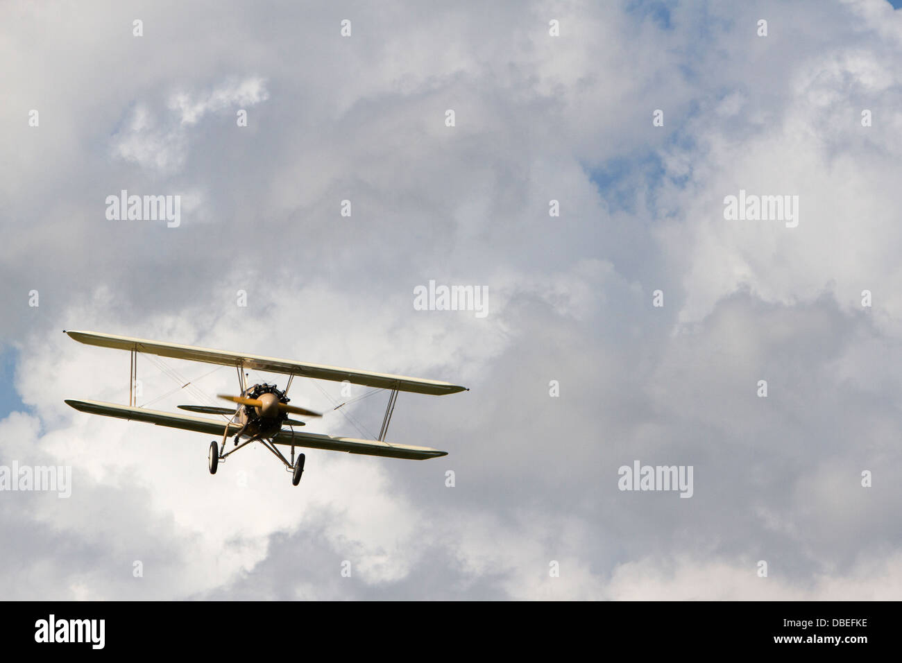 Biplane in flight against a blue sky with cumulus clouds Stock Photo ...