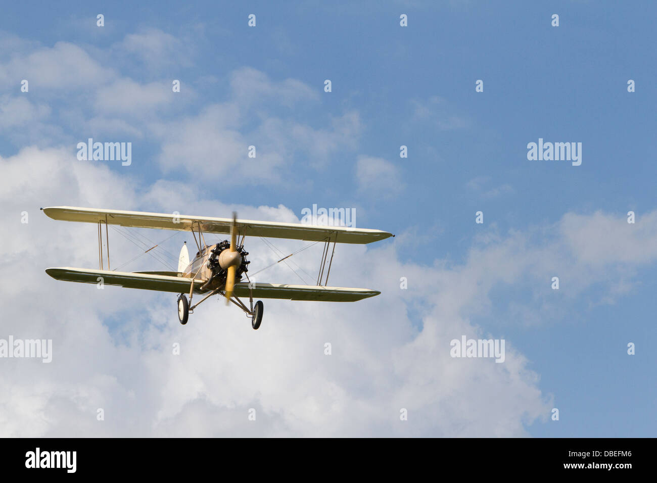 Biplane in flight against a blue sky with cumulus clouds Stock Photo ...