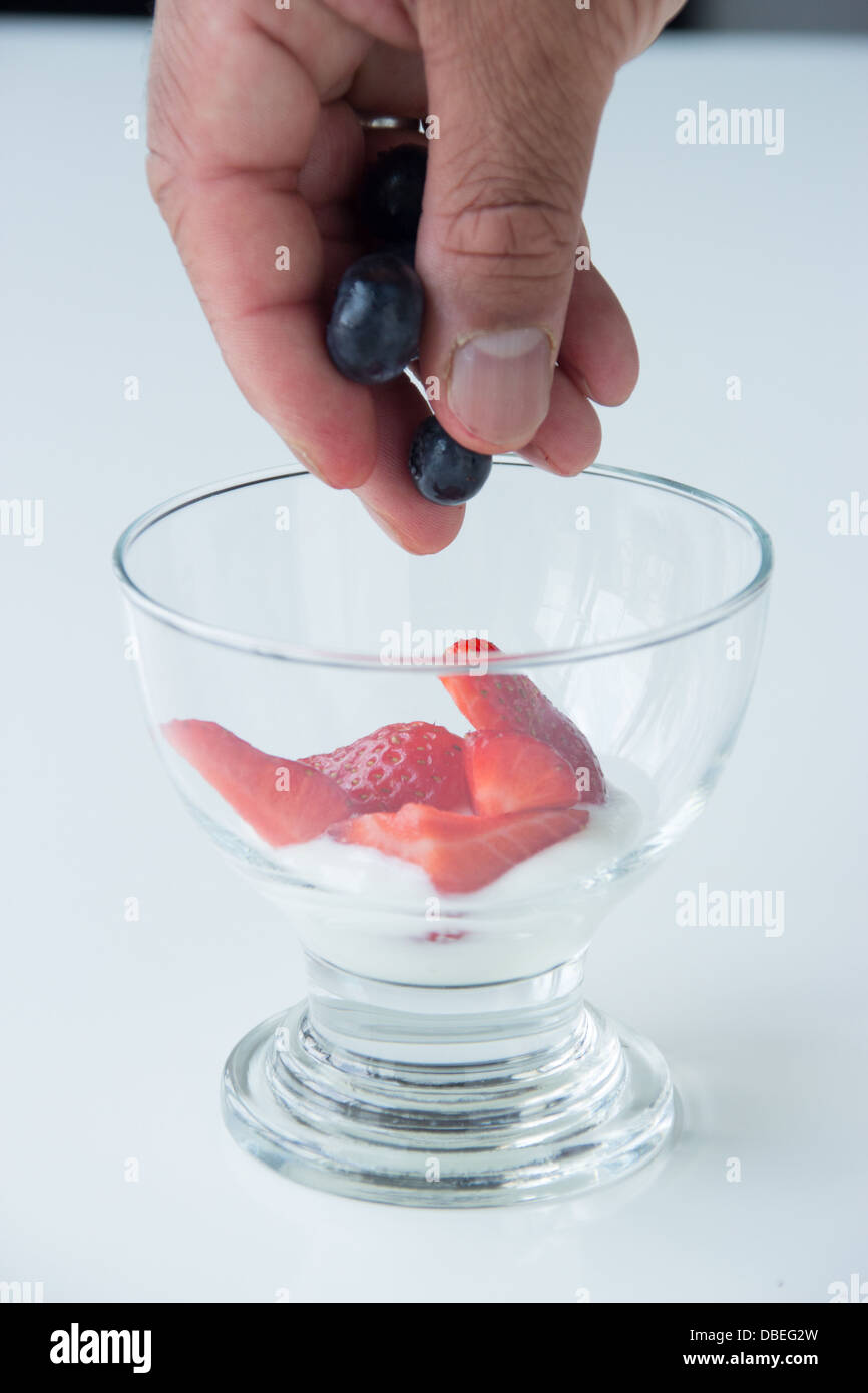 Hand preparing berries and yogurt Stock Photo - Alamy