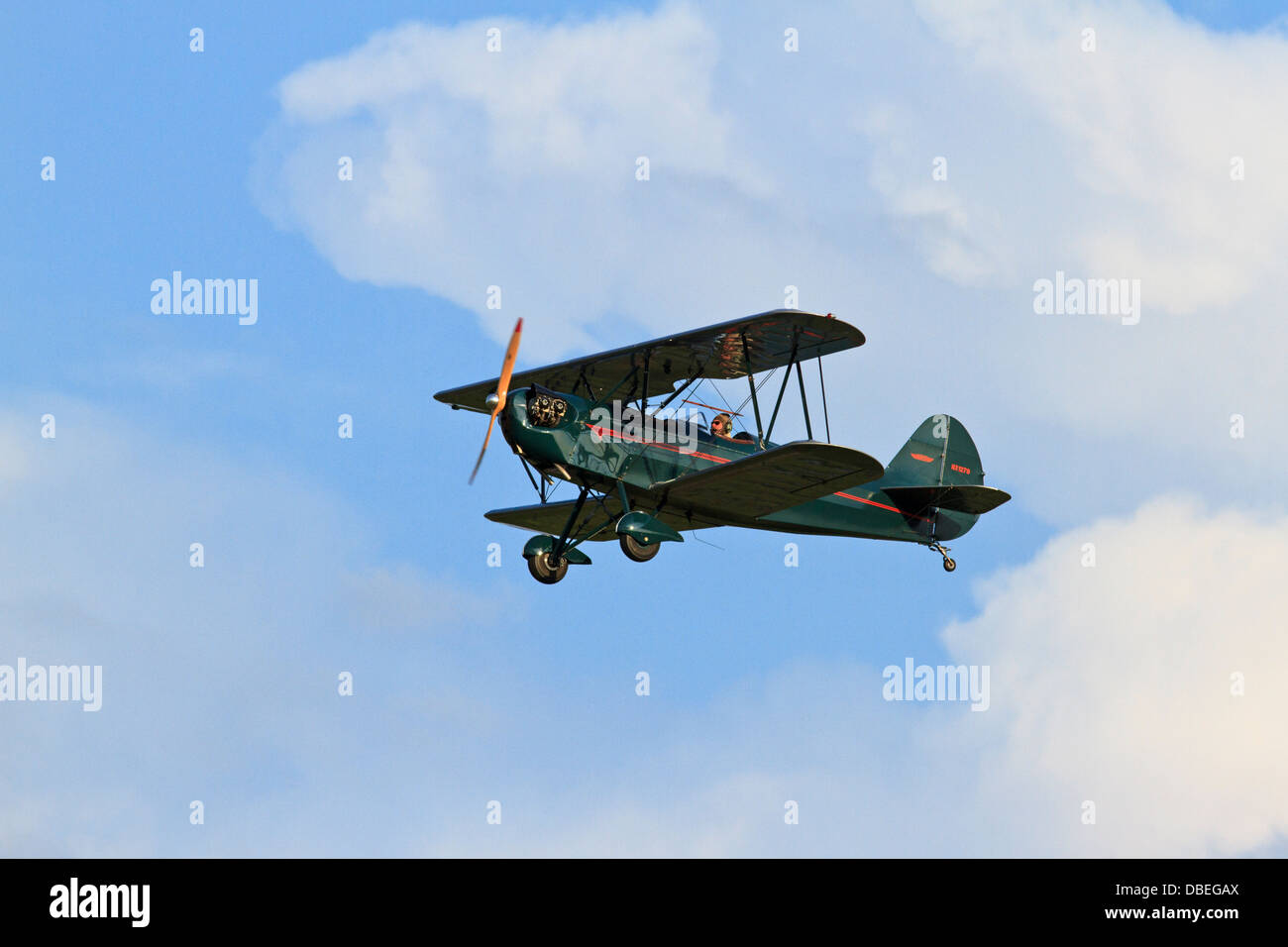 Biplane in flight against a blue sky with cumulus clouds Stock Photo ...