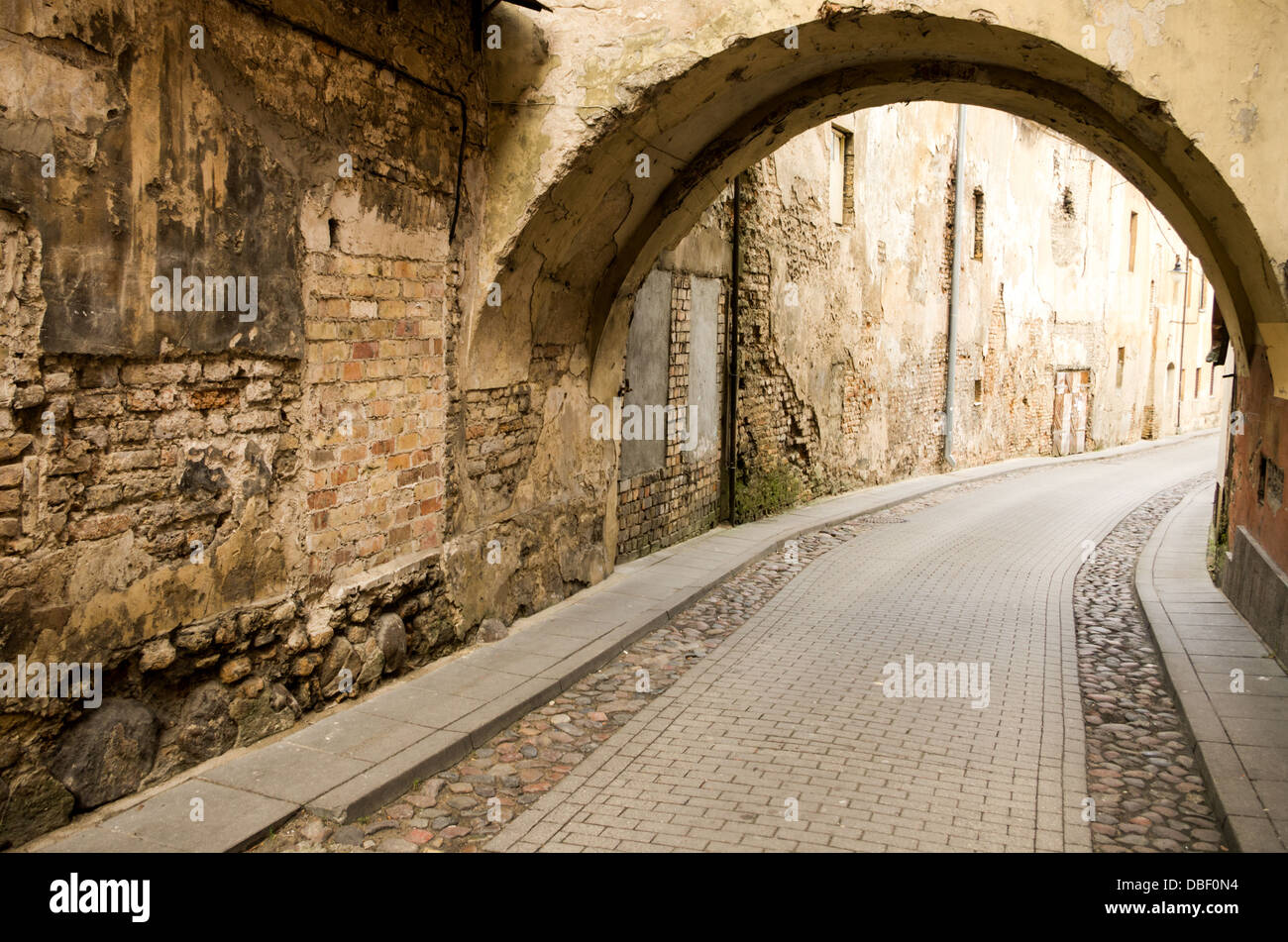 An old town scene with an old brick wall buildings and an arch and a ...