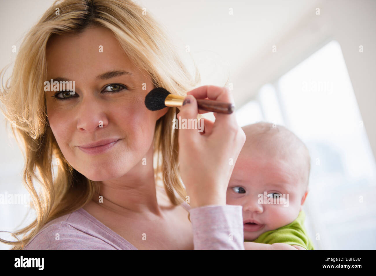 Caucasian mother with baby applying makeup Stock Photo - Alamy