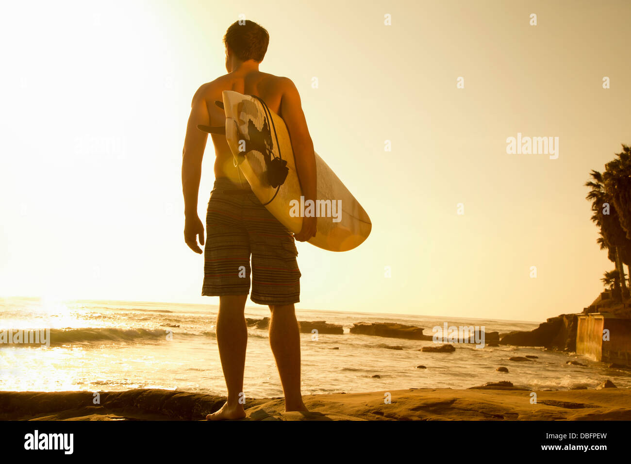 Man carrying surfboard on beach Stock Photo - Alamy