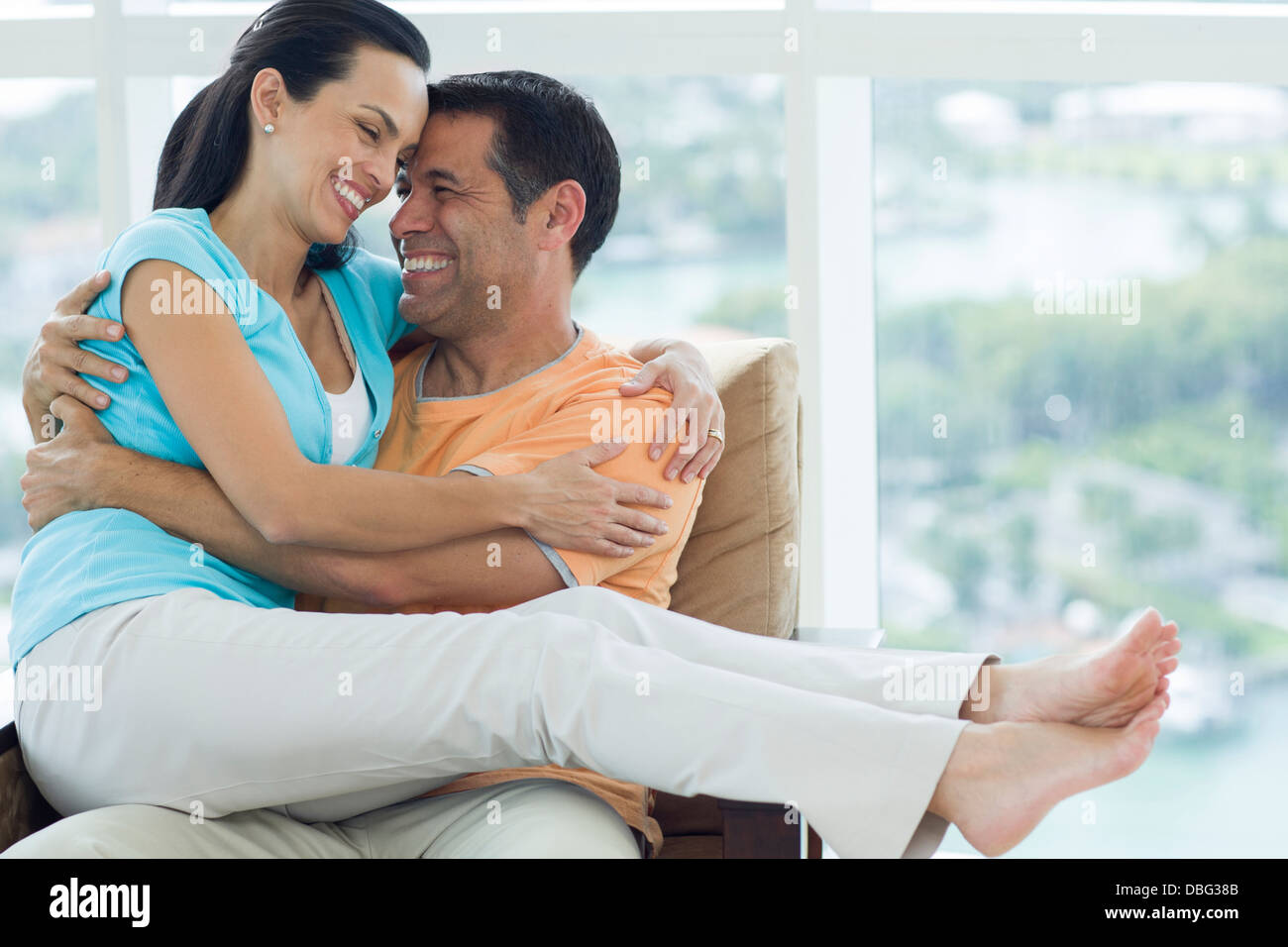 Hispanic couple hugging in armchair Stock Photo - Alamy