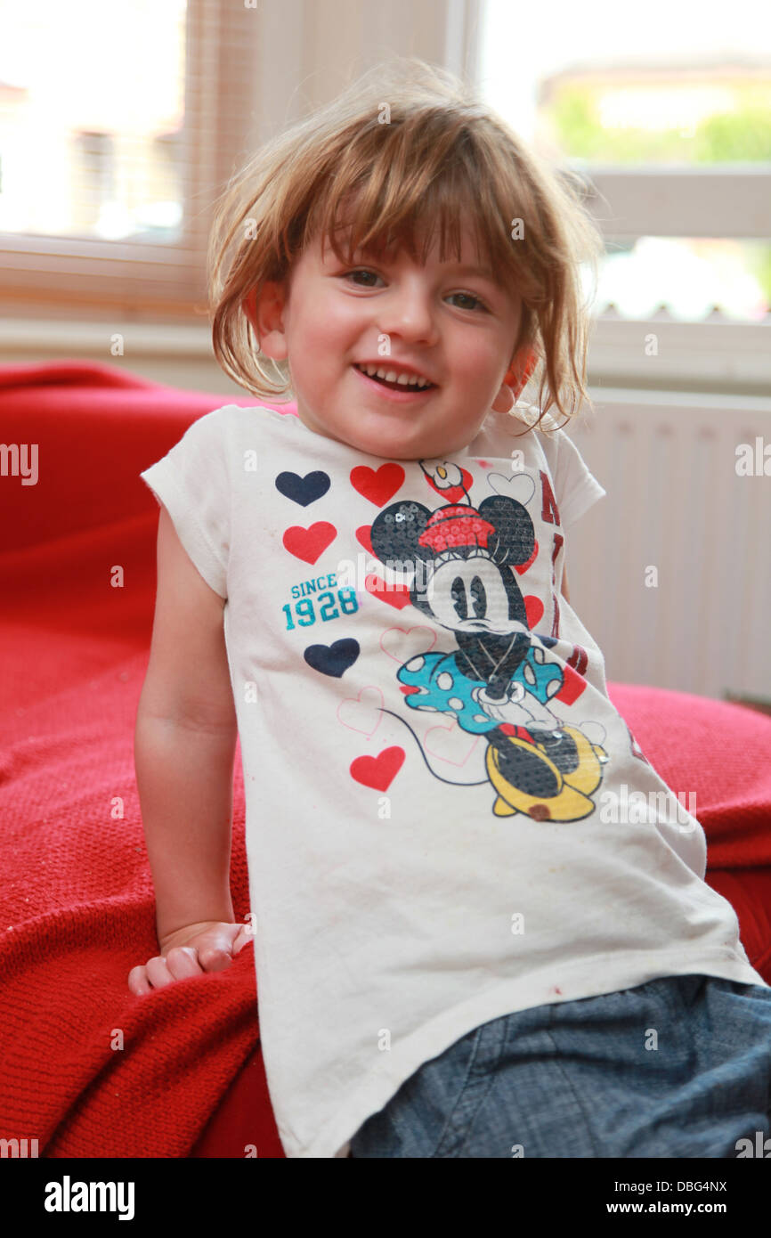 Toddler girl sitting on a red sofa Stock Photo - Alamy