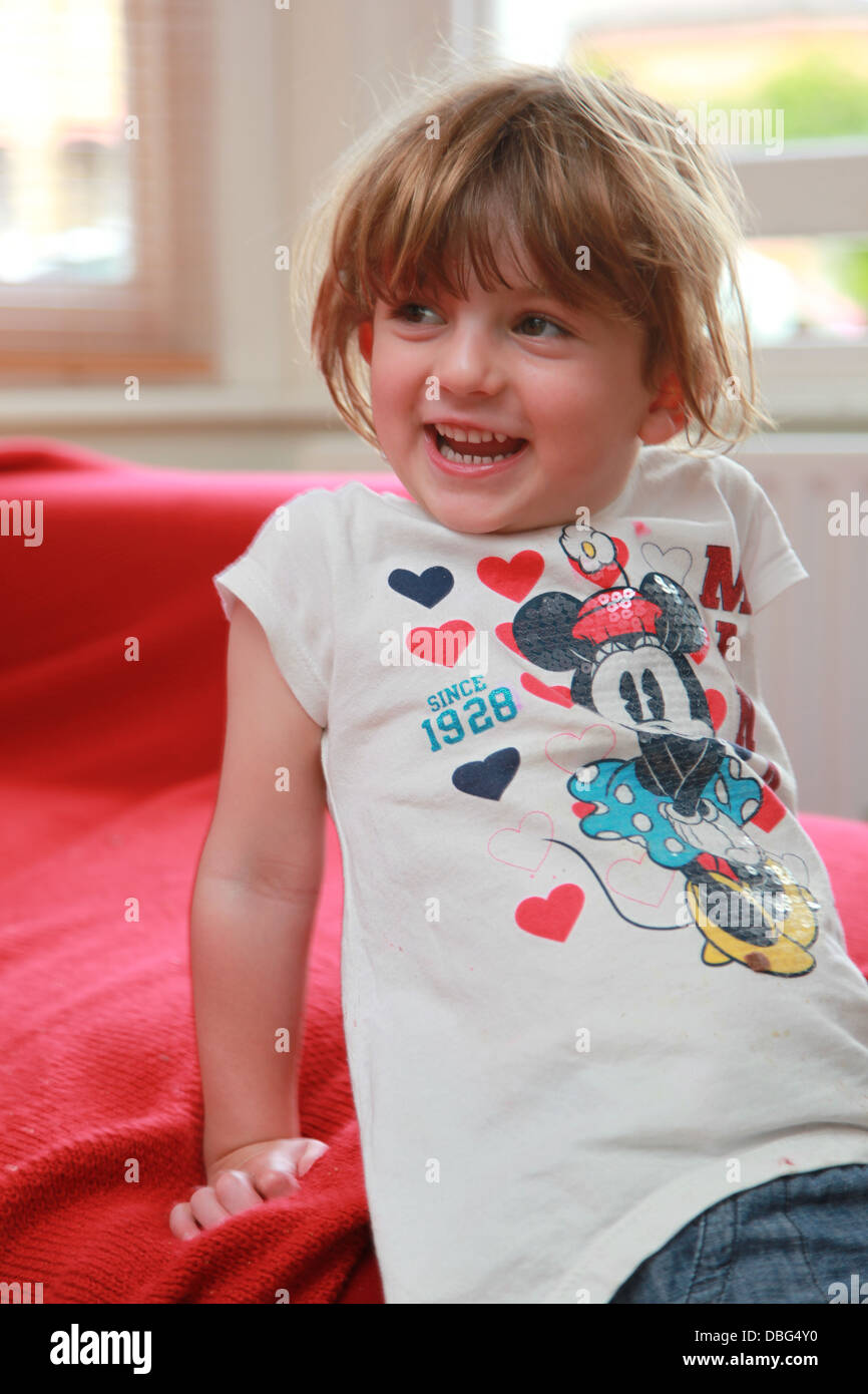 Toddler girl sitting on a red sofa Stock Photo - Alamy
