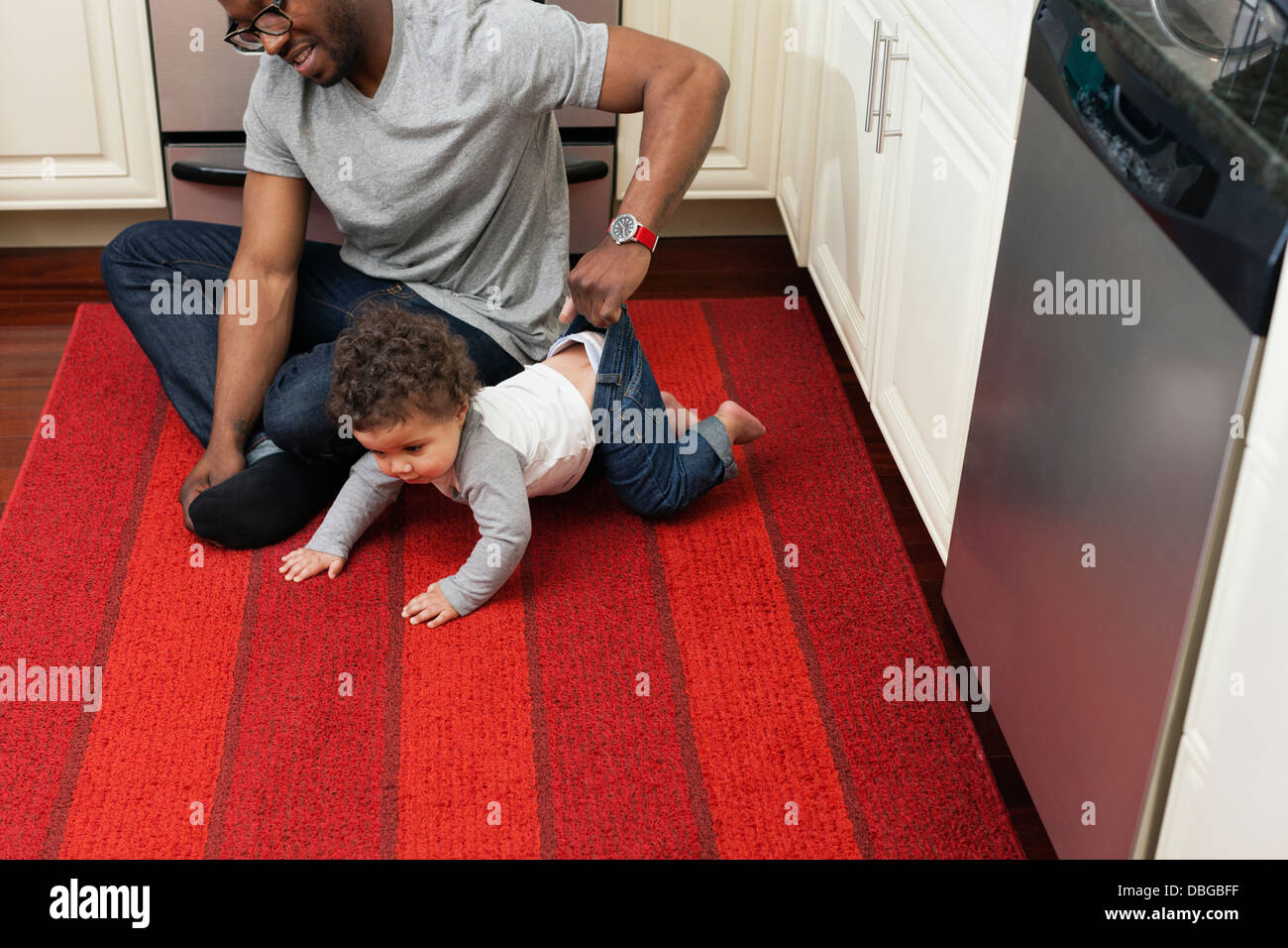 Father helping baby crawl in kitchen Stock Photo - Alamy