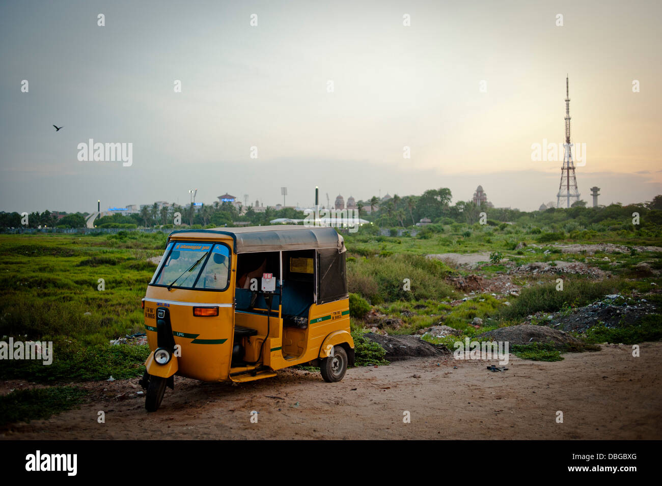 A yellow auto-rickshaw is parked on Marina Beach in the Southern Indian ...