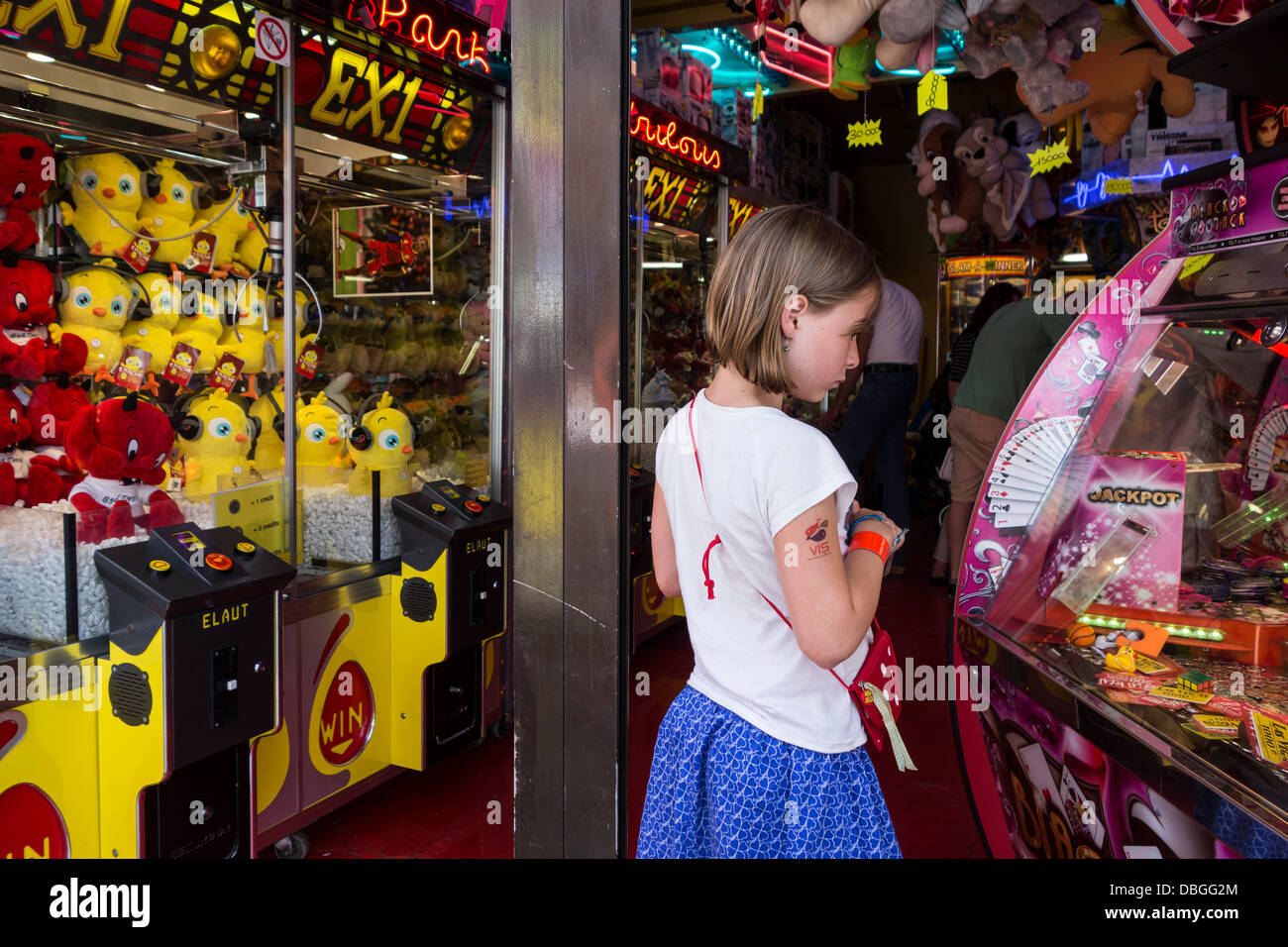 Arcade with claw crane game machines and child looking at coin pusher ...