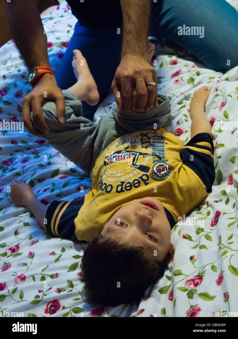 A young boy undergoes rigorous stretching exercises in physiotherapy ...