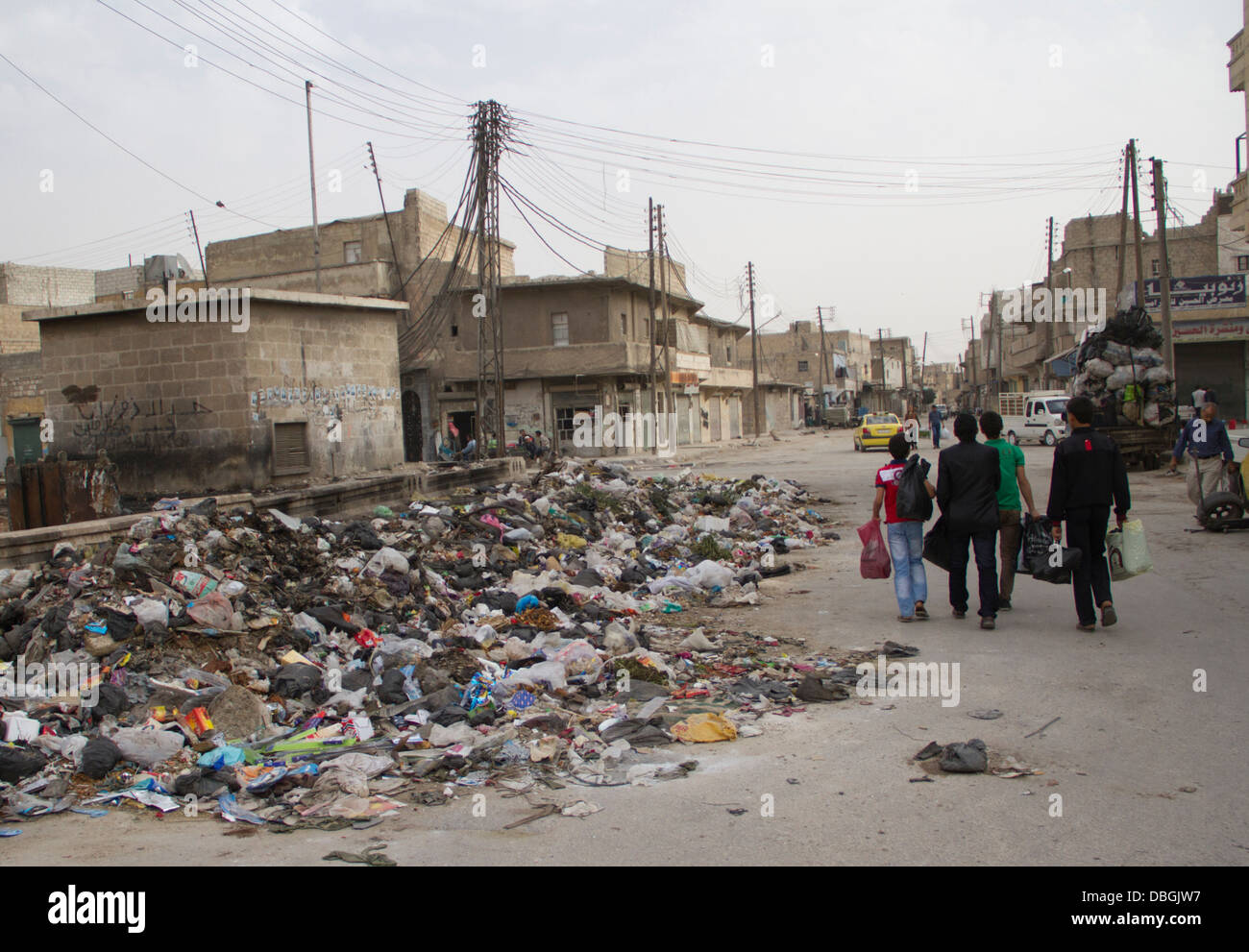 October 21, 2012 - Aleppo, Syria: People walk by mounds of trash on the ...