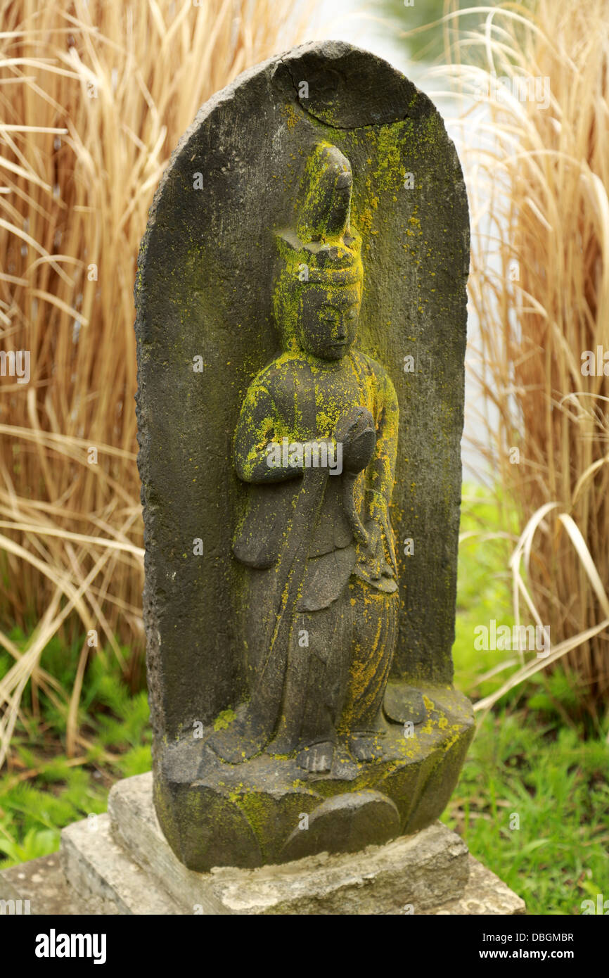 moss covered Asian stone statue in garden Stock Photo - Alamy