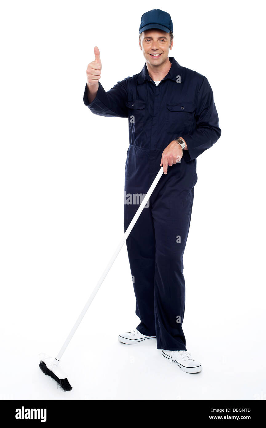 Cleaning guy holding broom and showing thumbs up Stock Photo - Alamy