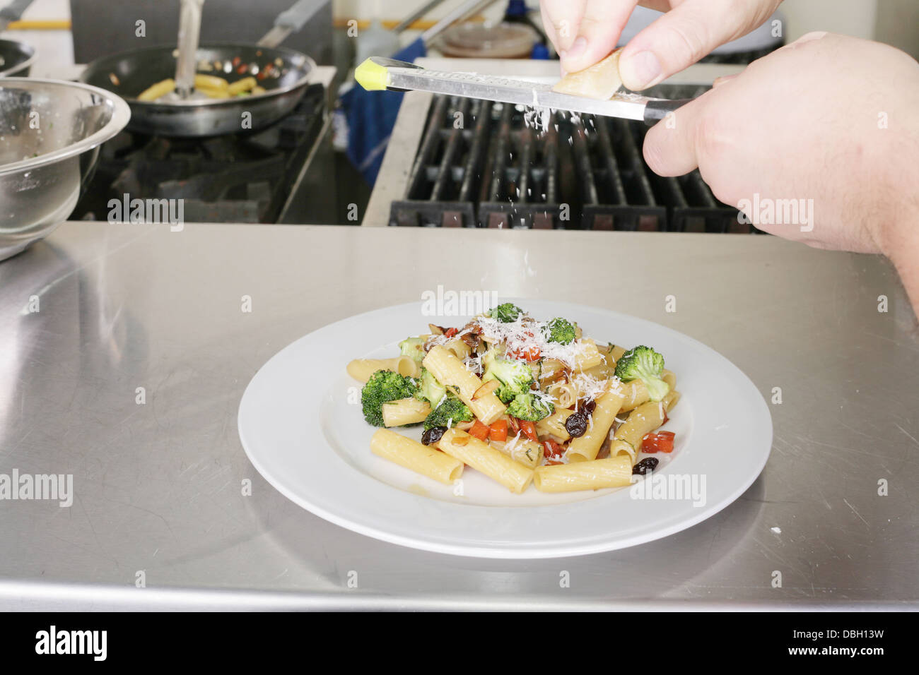Italian food. Chef putting parmesan over a rigatoni with vegetables ...