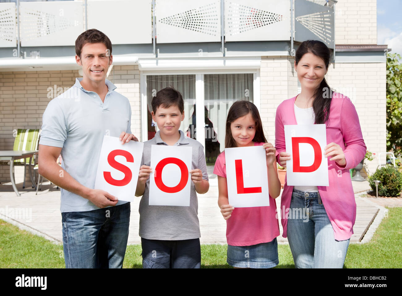 Family holding a sold sign outside their home Stock Photo - Alamy