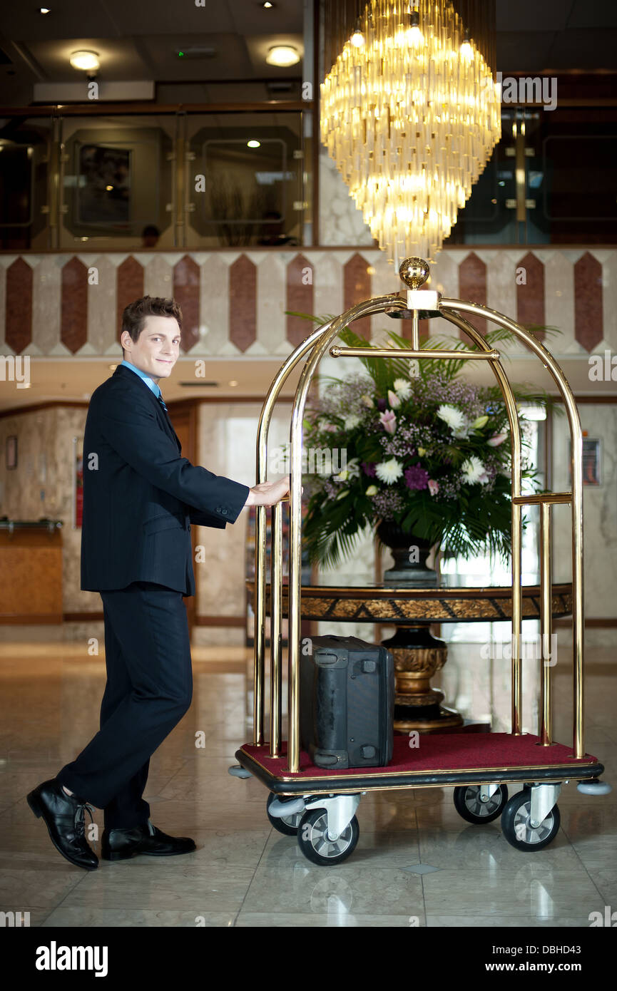Handsome concierge pushing the luggage cart Stock Photo - Alamy