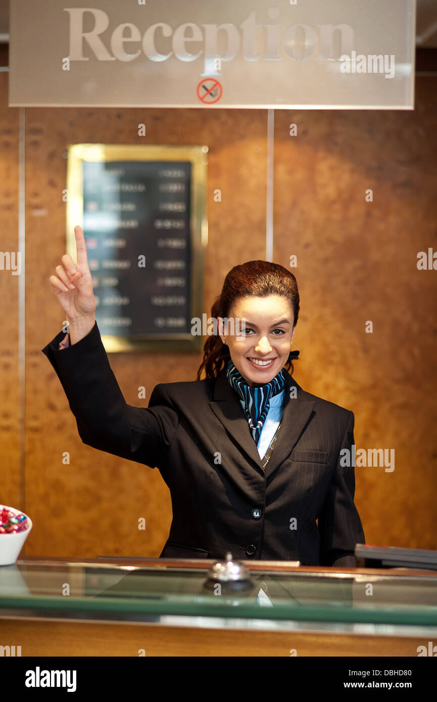 Beautiful female receptionist indicating upwards Stock Photo - Alamy
