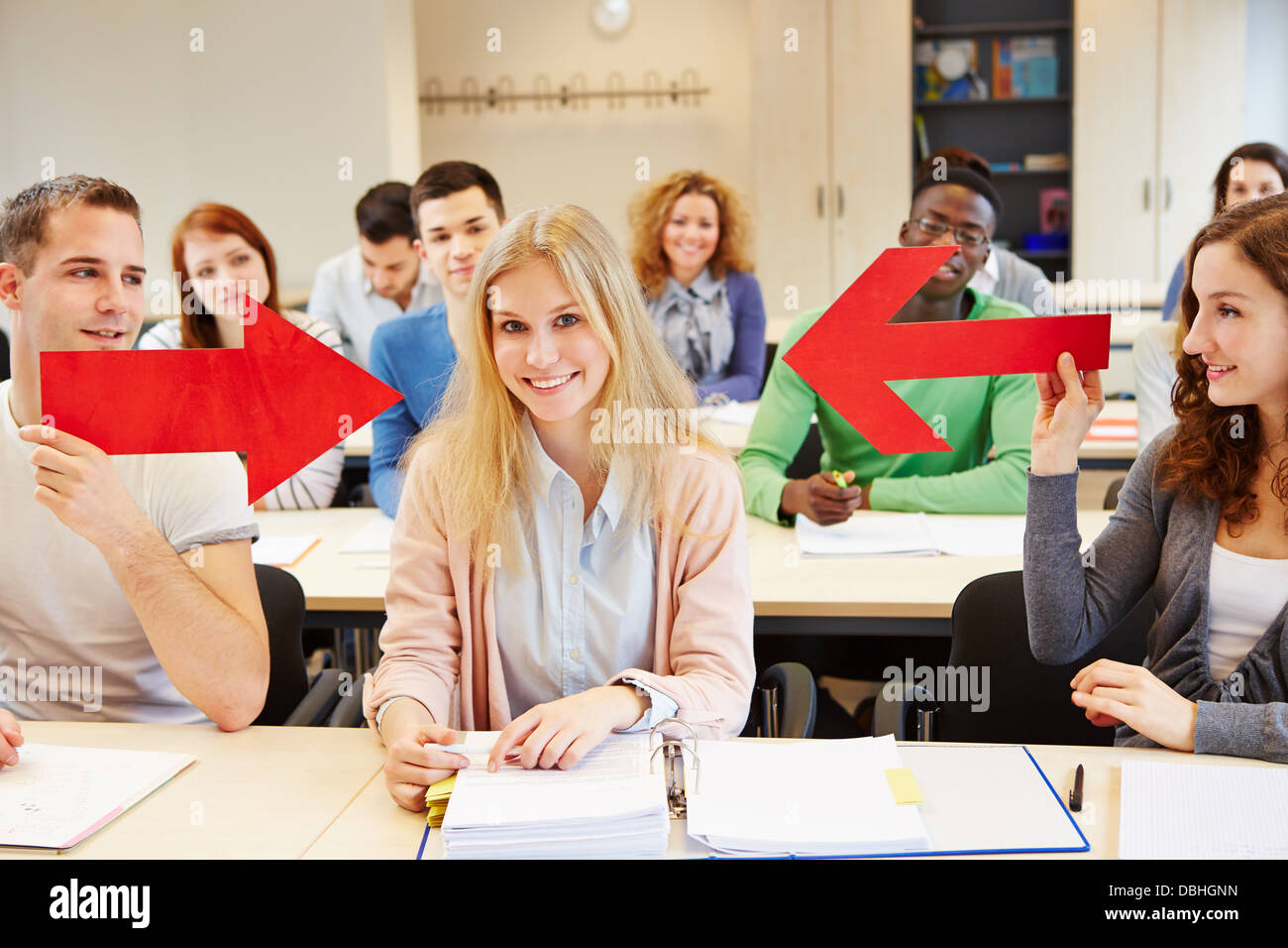 Students pointing two red arrows to young student in classroom Stock ...