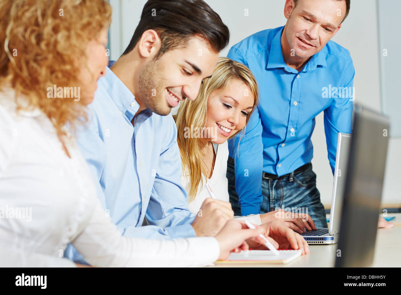 Students learning together in college with teacher and laptop computer ...