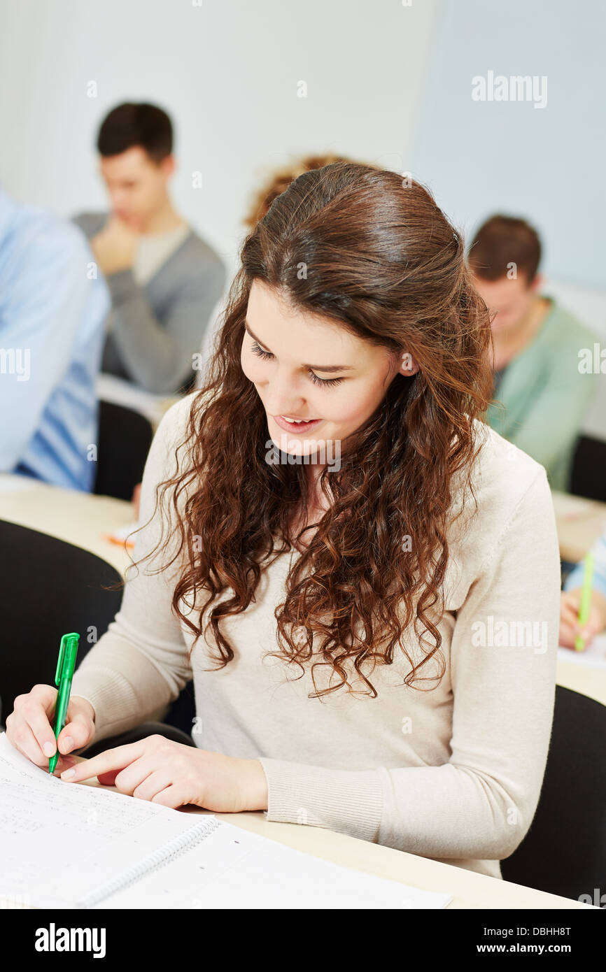 Happy female student taking notes in university course classroom Stock ...