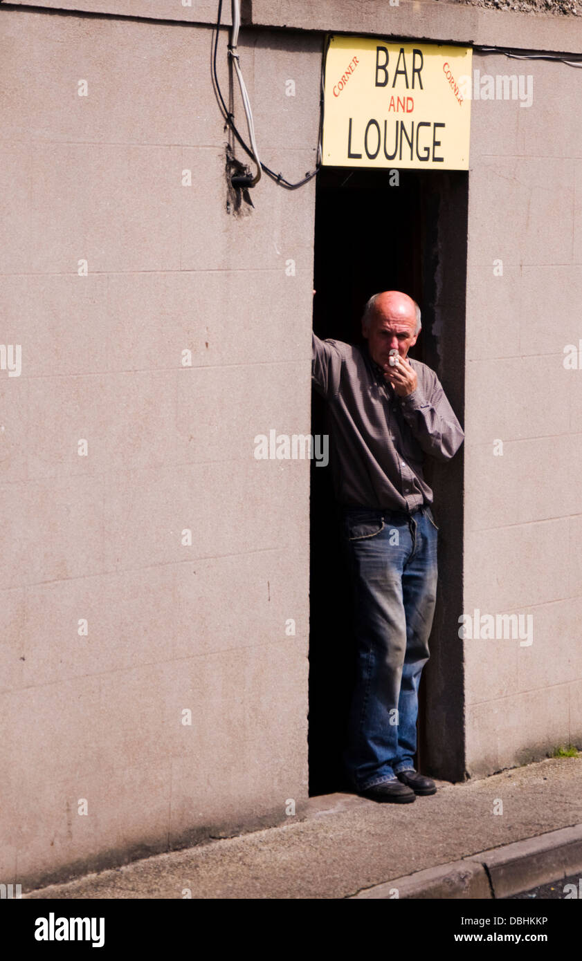 Man stands smoking outside a bar in Dungloe County Donegal Ireland ...