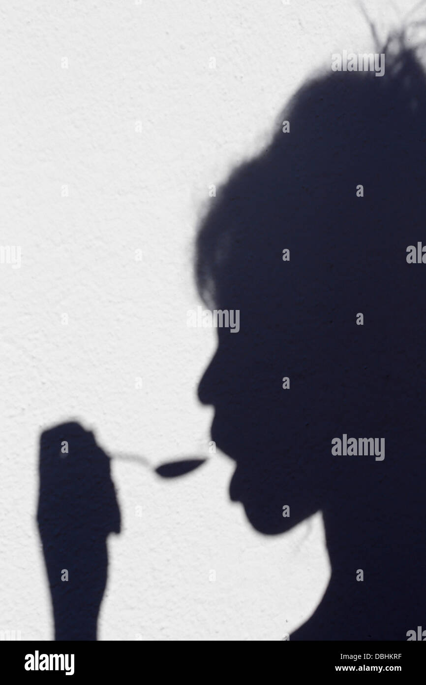 Shadow of a woman eating with a spoon Stock Photo - Alamy