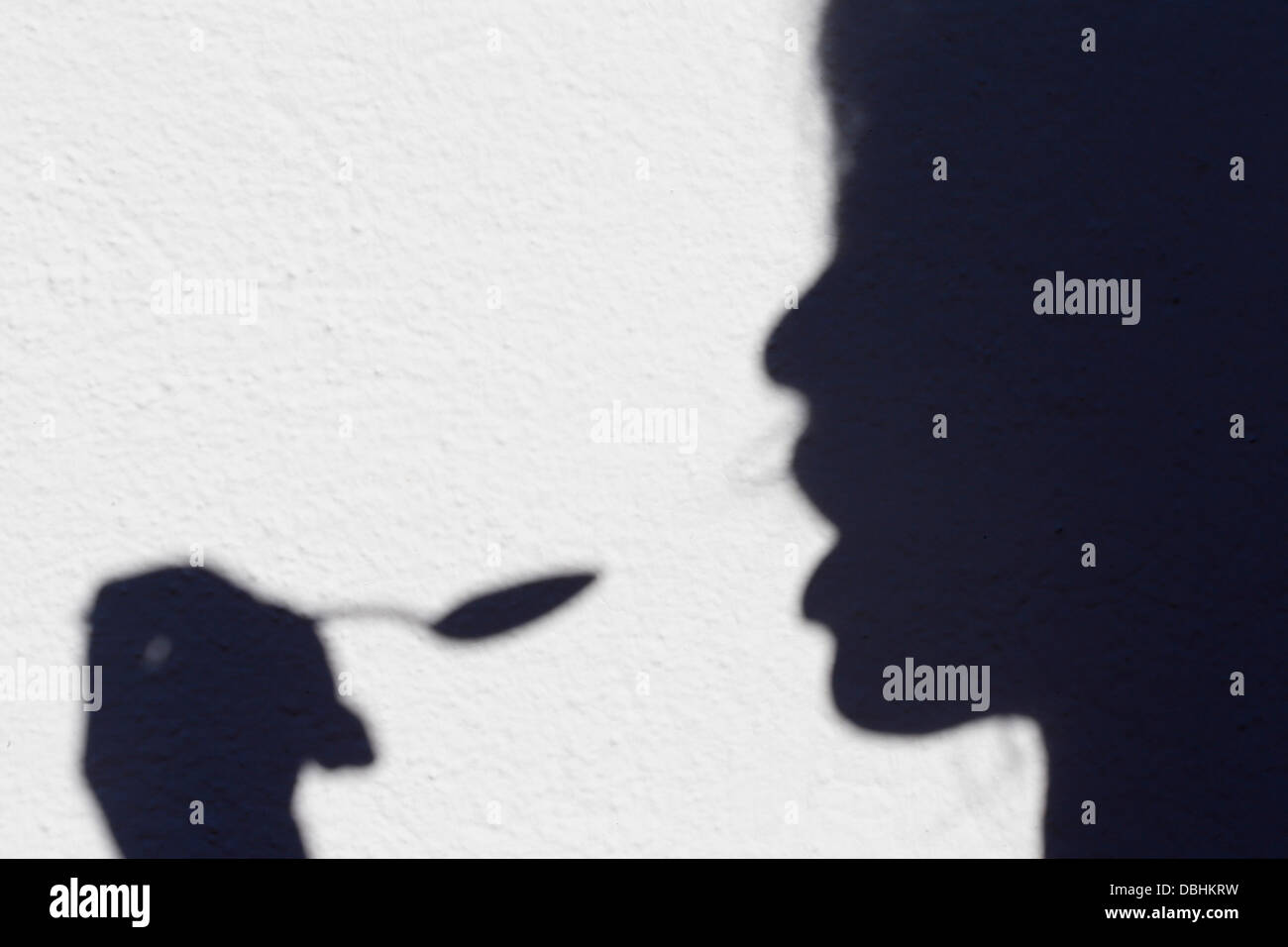 Shadow of a woman eating with a spoon Stock Photo - Alamy