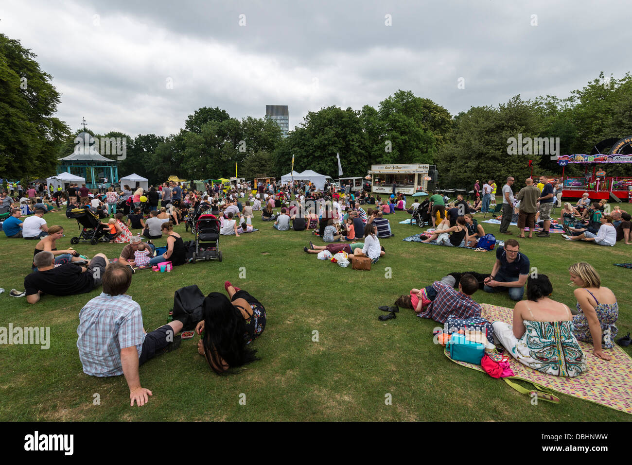 Crowds of people sitting on grass watching a band at open air concert ...