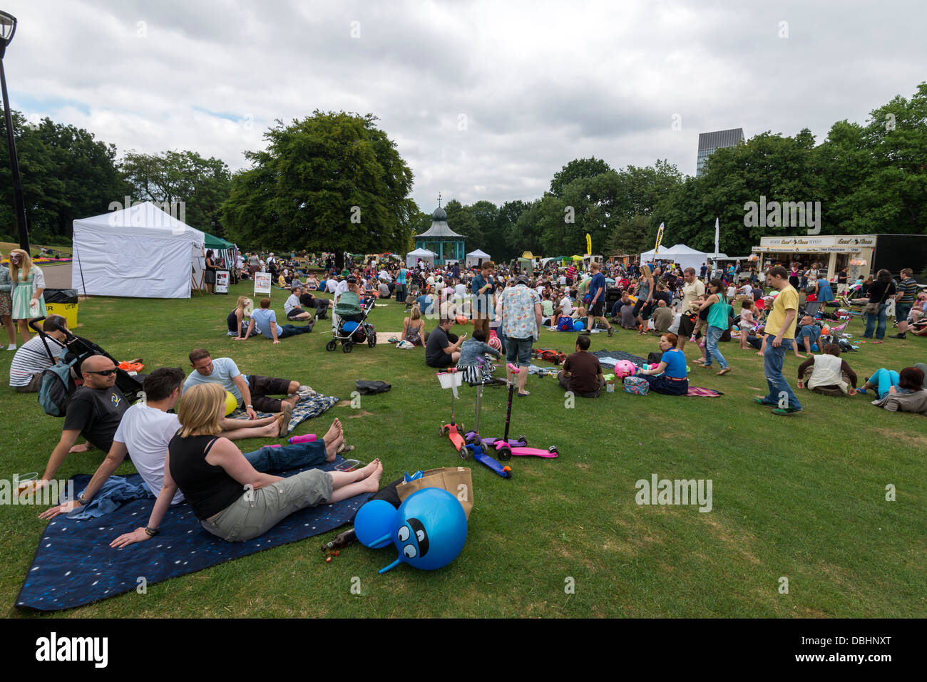 Crowds of people sitting on grass watching a band at open air concert ...