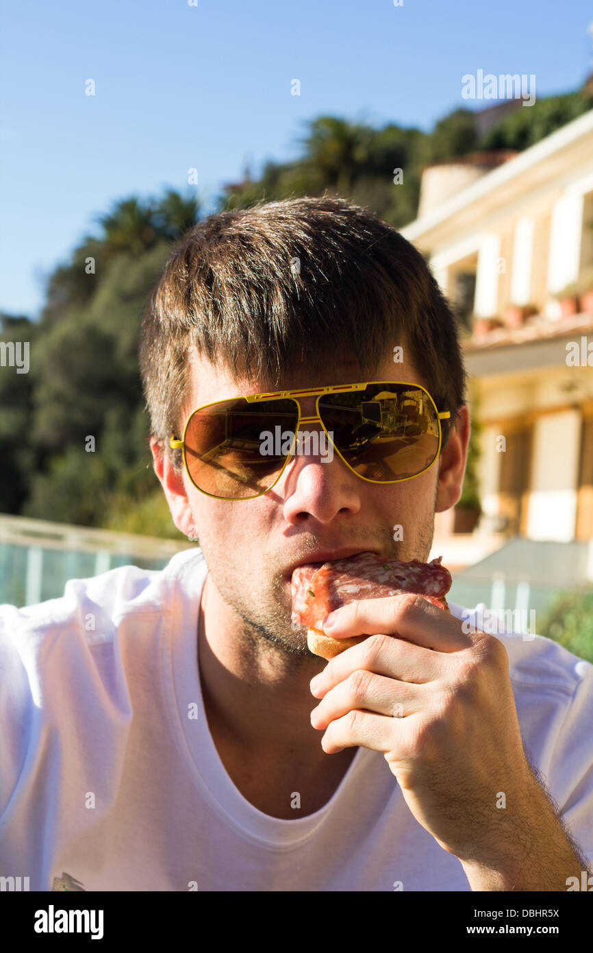 Man Eating A Salami Bread For Breakfast Outdoors In The Sun Stock Photo ...