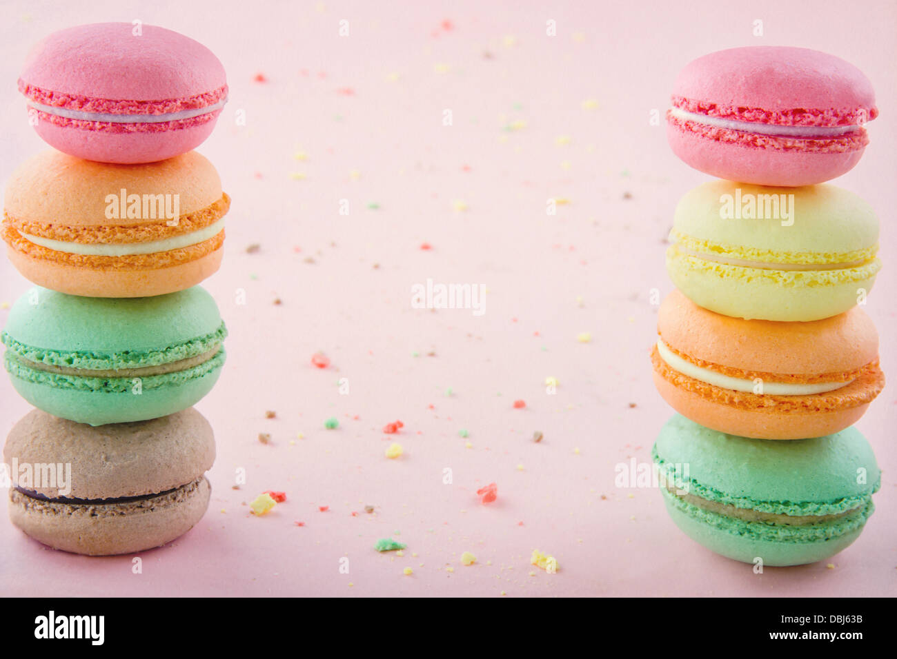 Two piles of colorful macaroons on pastel pink background with small ...