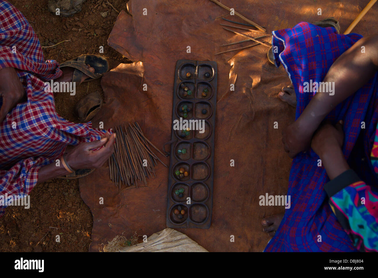 Masai tribesmen playing traditional board game called Enkeshui ...