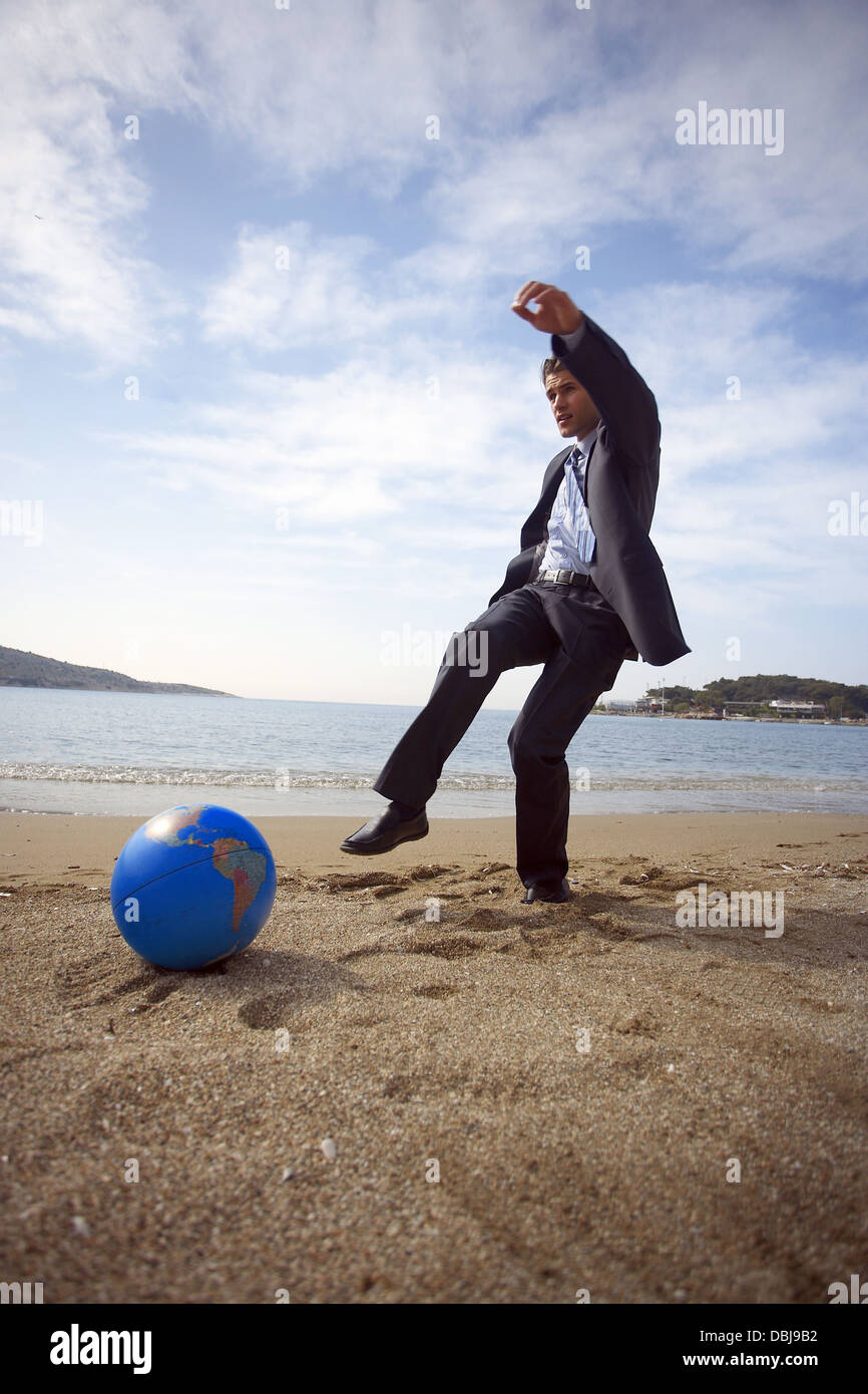 Businessman on beach with globe beach ball Stock Photo - Alamy
