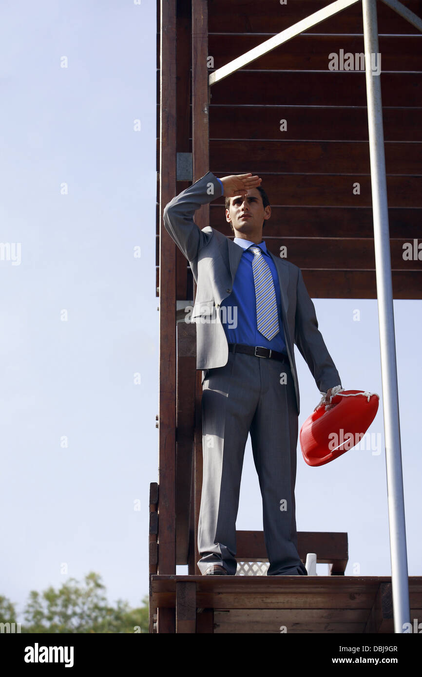 Businessman on life guard stand with life preserver Stock Photo - Alamy