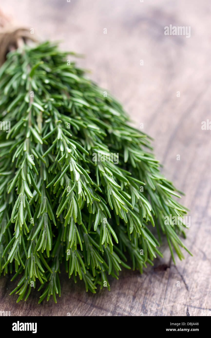 Bunch of green fresh rosemary herbs on rustic wooden table background ...