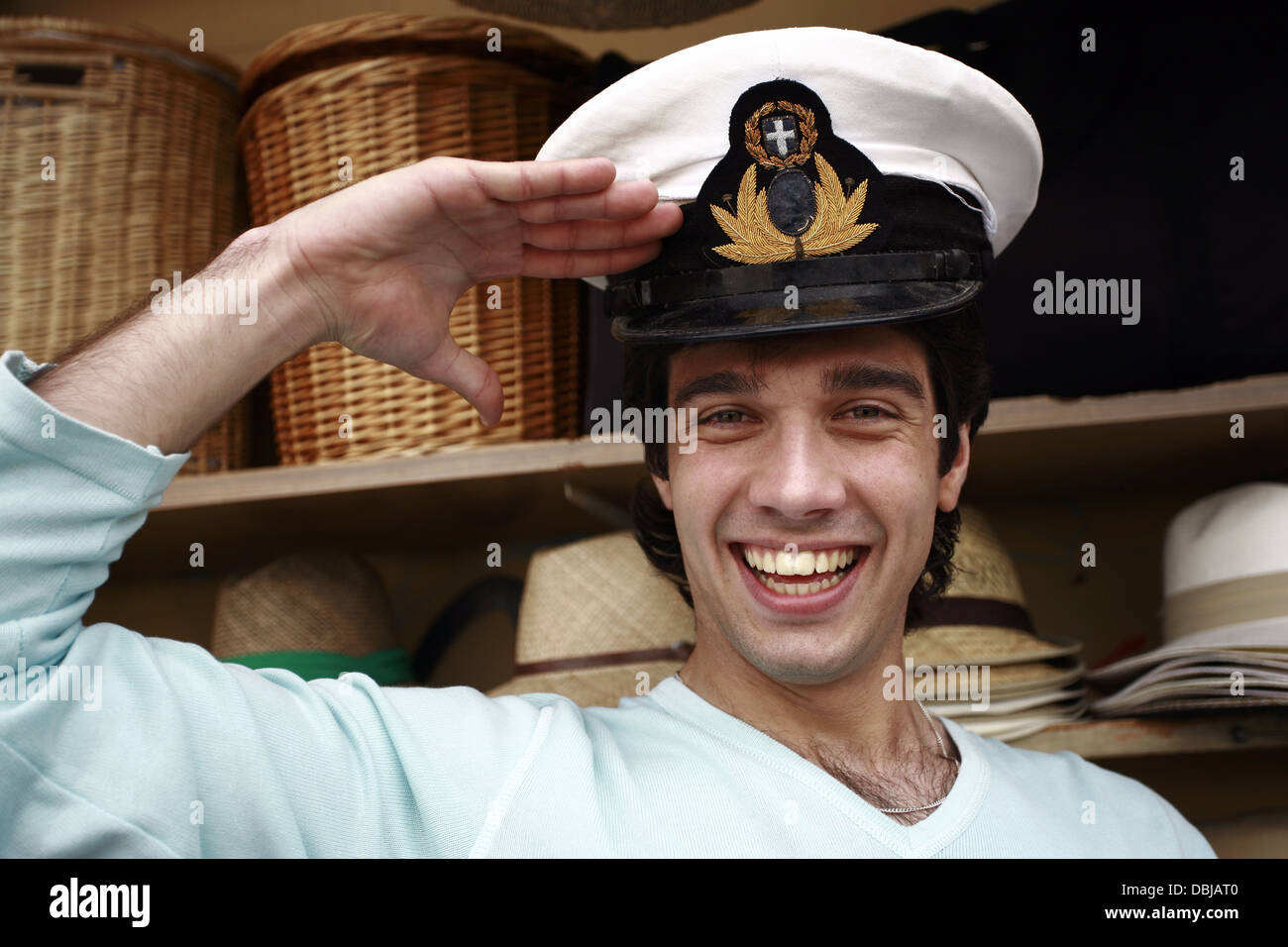 Man trying on naval hat, saluting Stock Photo - Alamy