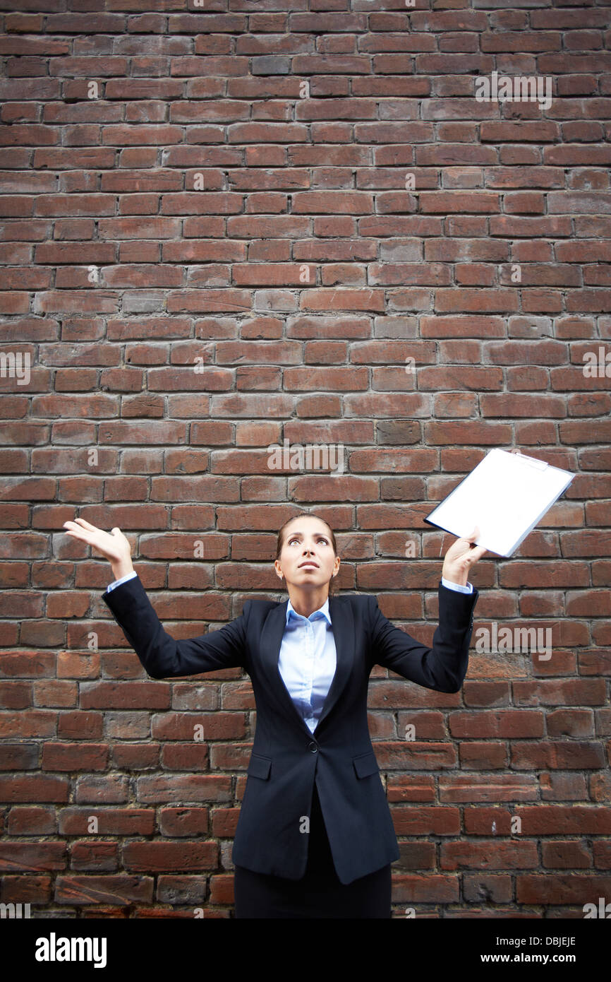 Image of perplexed businesswoman with open palms on background of brick ...