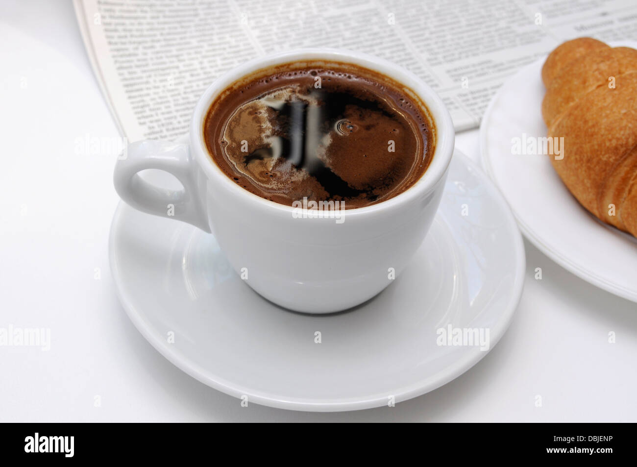 Cup of black coffee, croissants and breakfast accessories against a ...