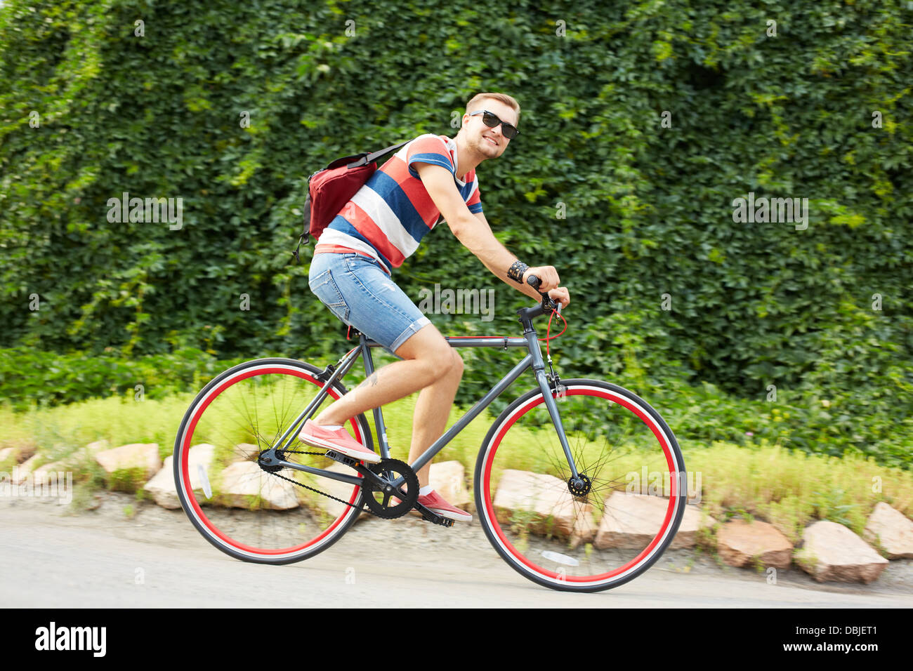 Portrait of happy guy riding bicycle in the park Stock Photo - Alamy