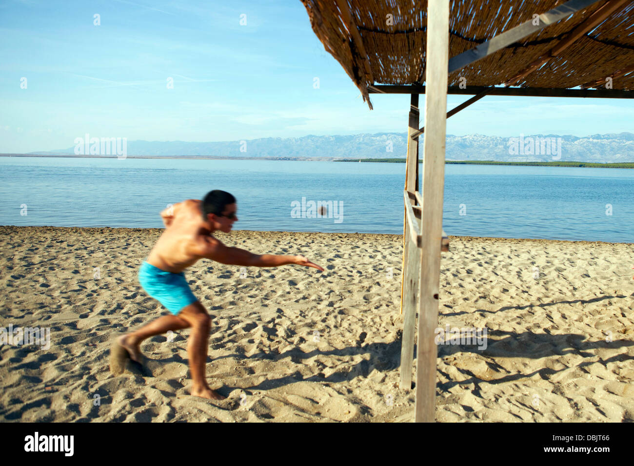 Young Man Playing ball on beach Stock Photo - Alamy