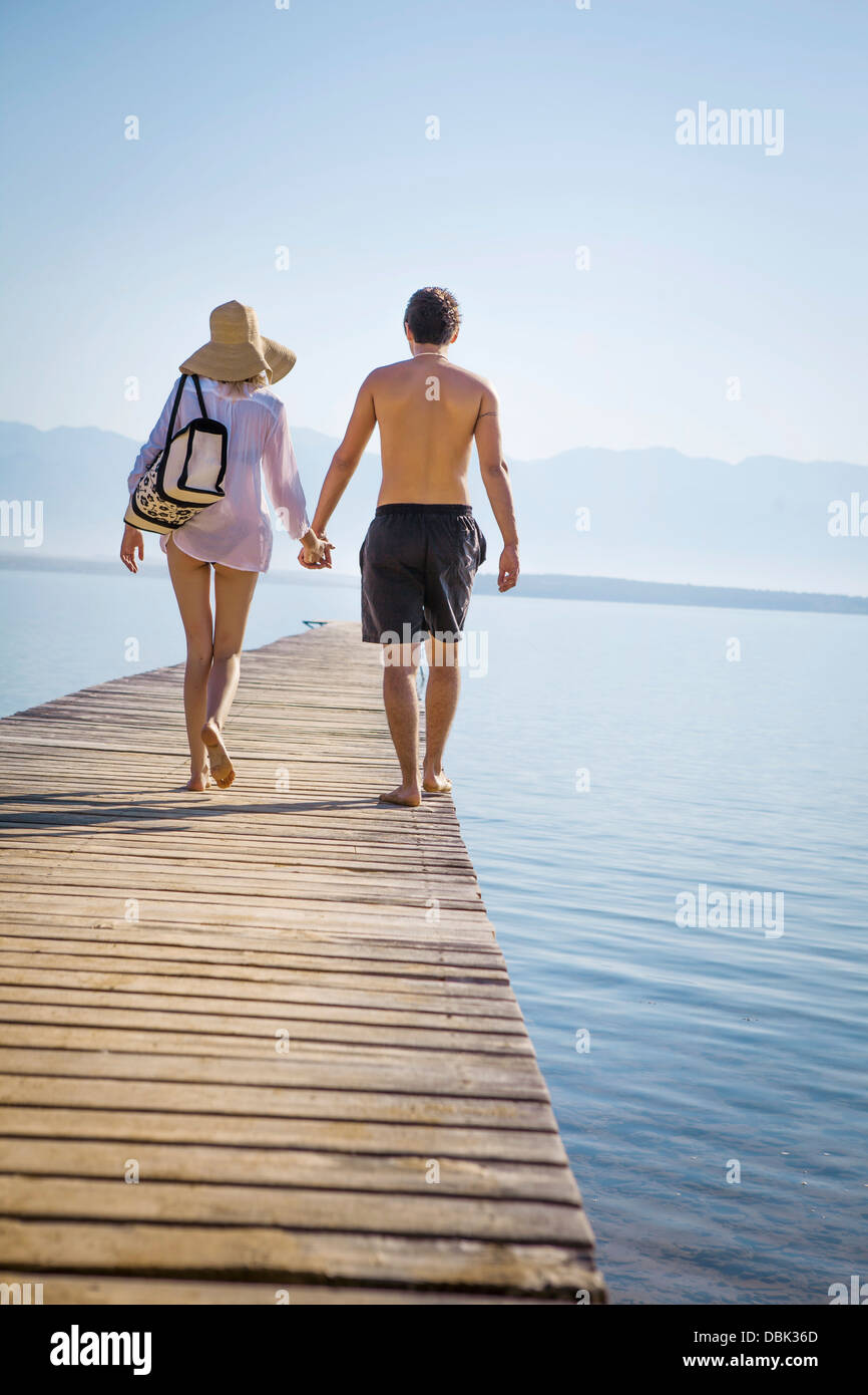 Croatia, Young couple in swimwear walking across boardwalk, rear view ...