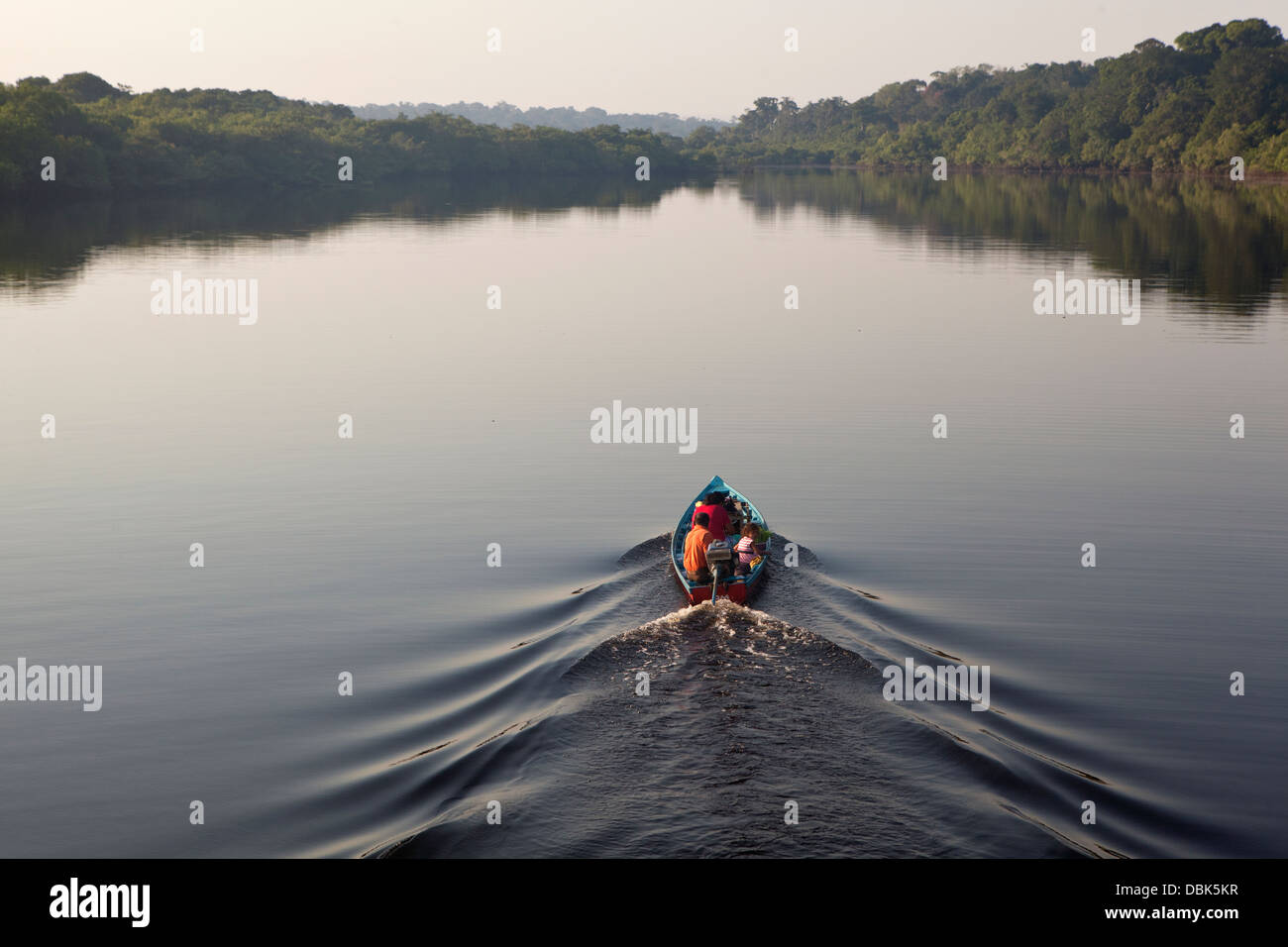 A family sails the Rio Negro on a boat on a quite morning, Amazonas ...
