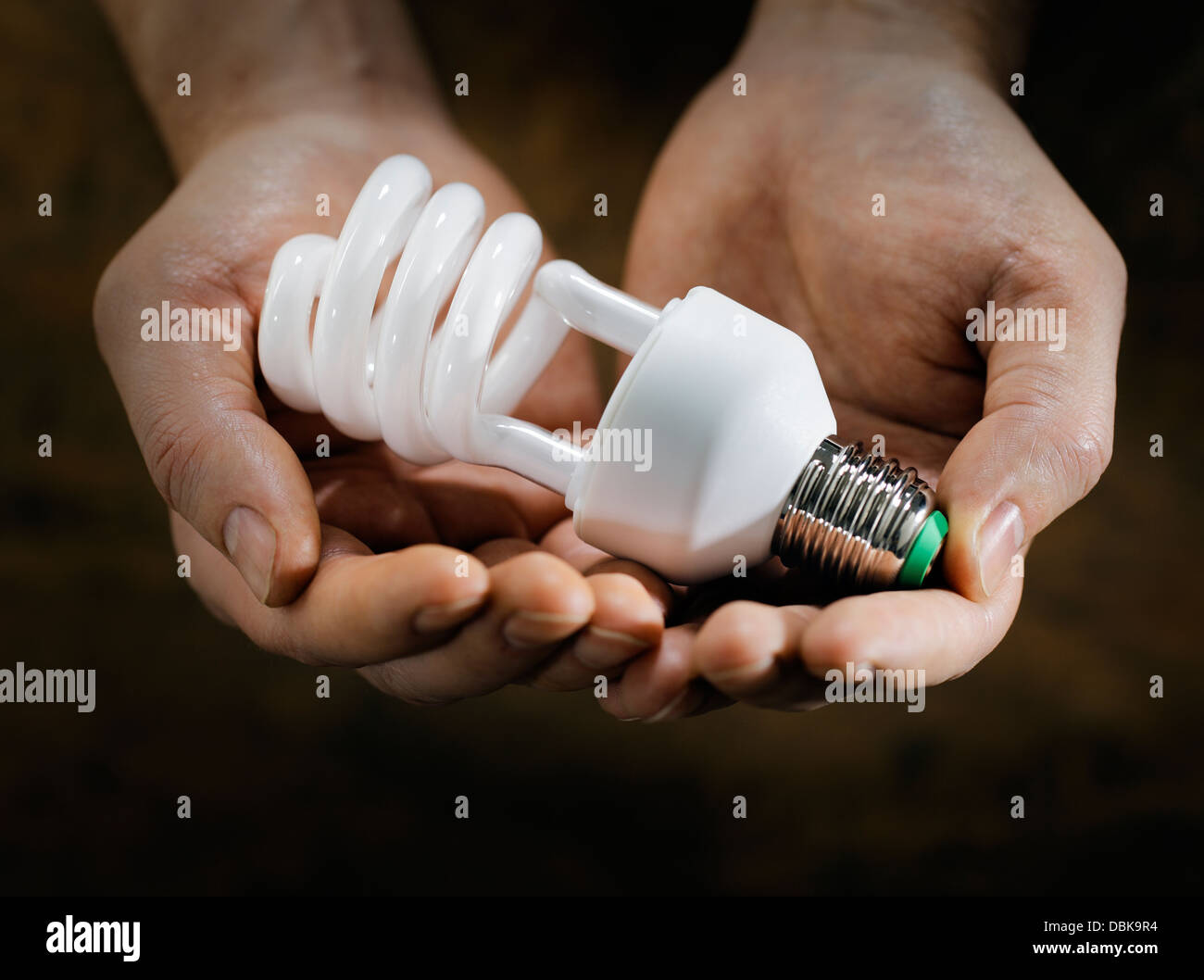 Man holding a spiral fluorescent bulb in his hands Stock Photo - Alamy